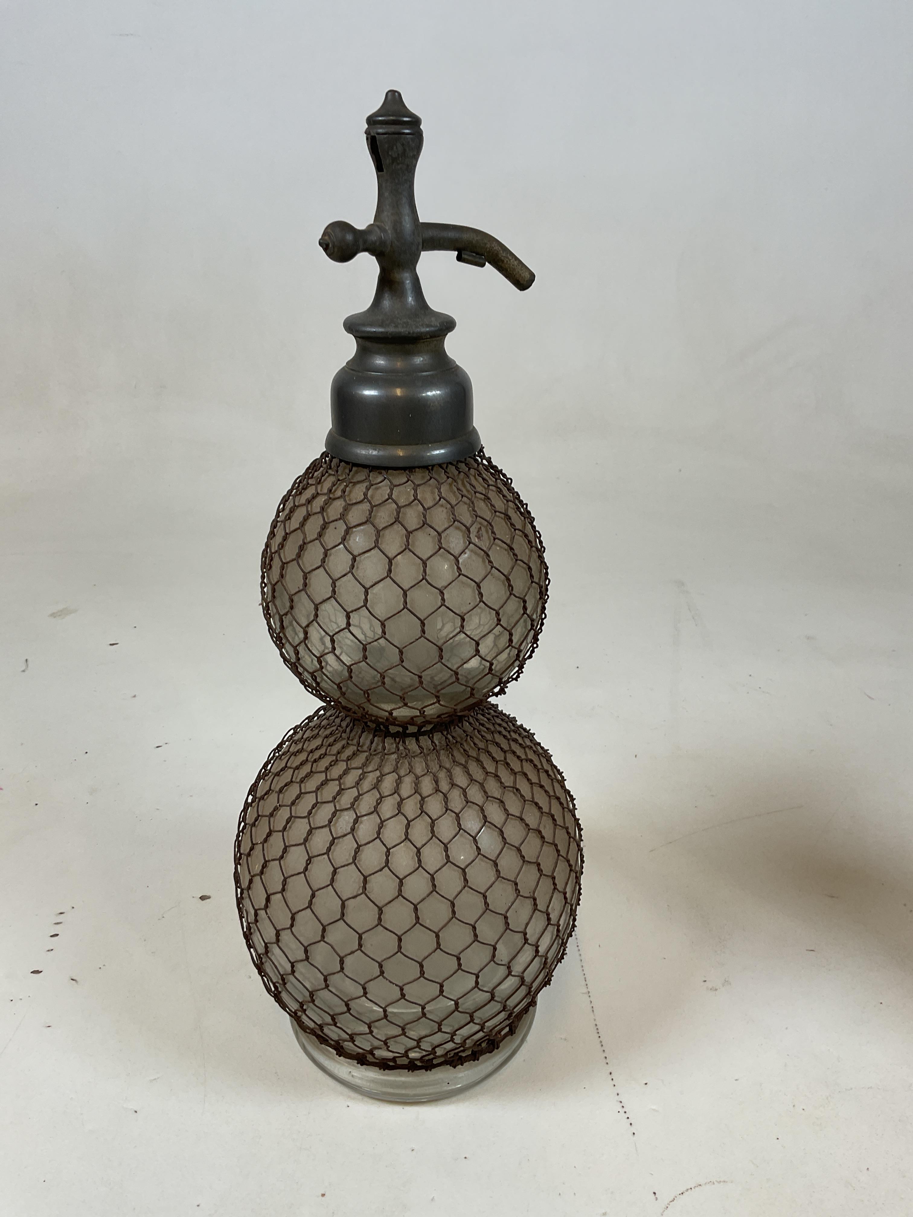 Lot 41 - A double gourd soda syphon with mesh cage and