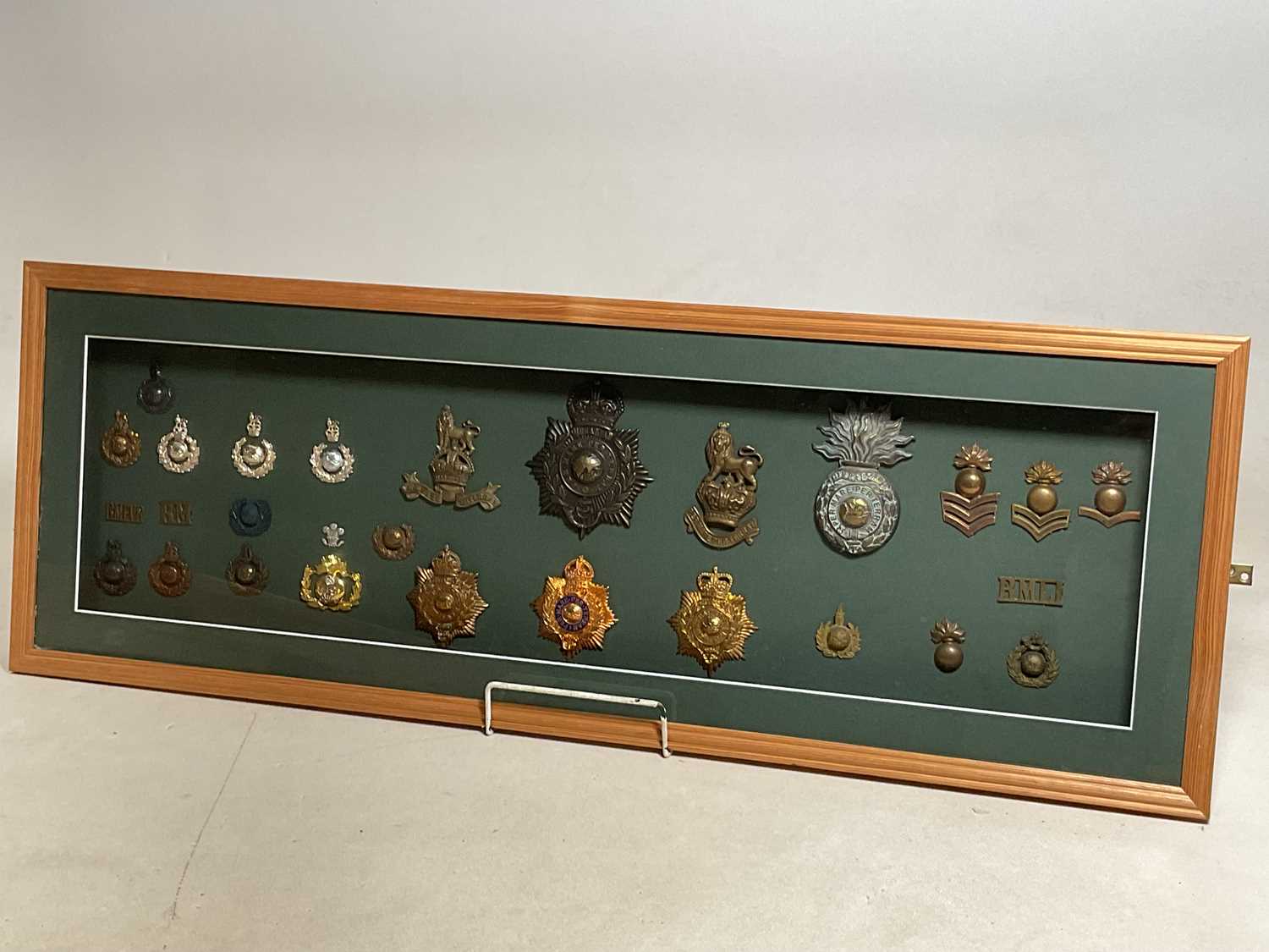 Lot 115 - A framed and glazed display of cap badges