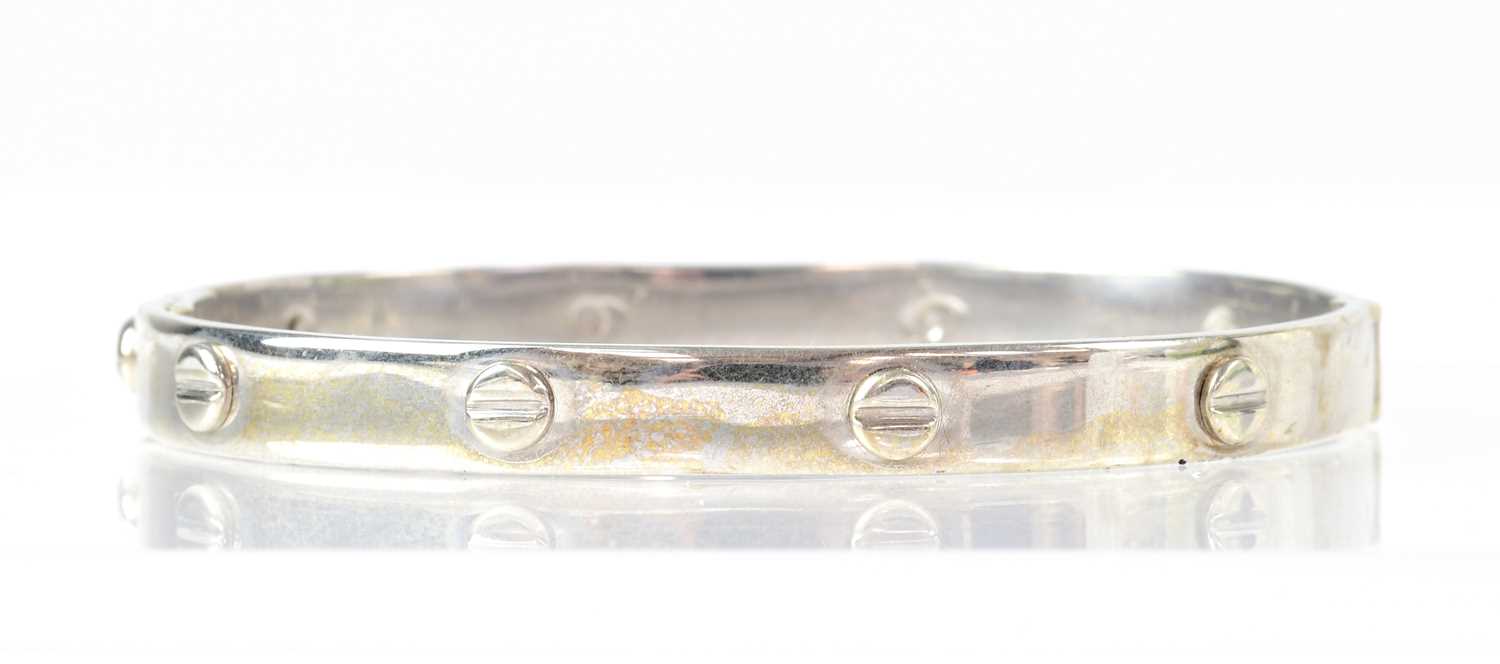 Lot 1069 - A 9ct white gold bangle with 'screw head'