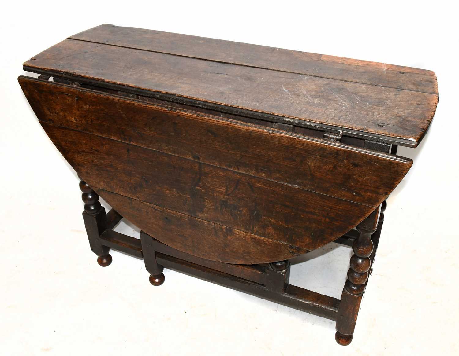 Lot 1692 - An antique oak oval drop-leaf table on